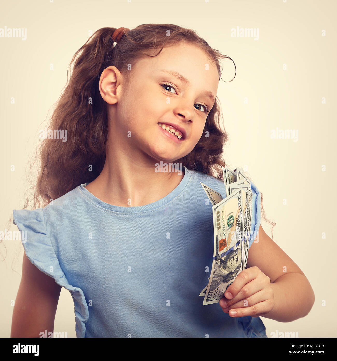 Happy laughing rich kid girl holding money hand on empty copy space ...