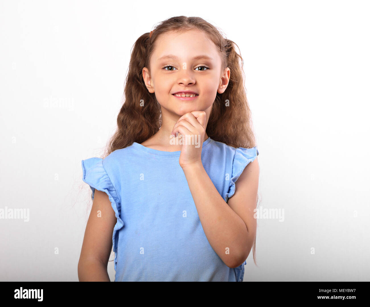 Beautiful cute happy smiling kid girl with hand under the face looking ...