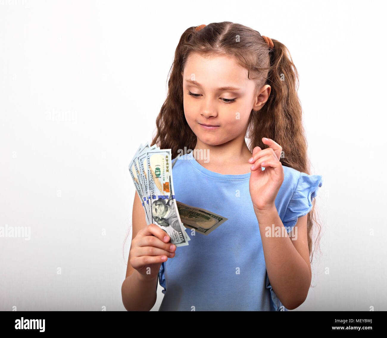 Happy smiling rich kid girl holding and count money on white background ...