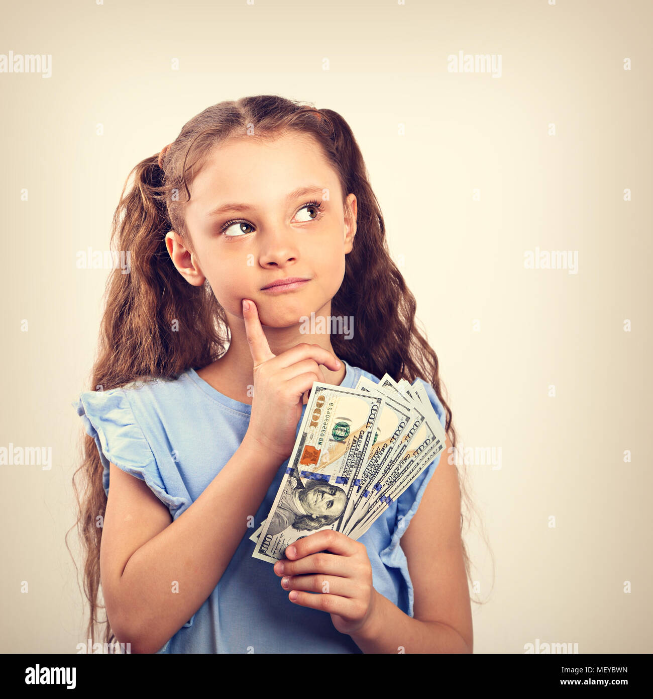 Happy smiling thinking rich kid girl holding money the hand and looking ...