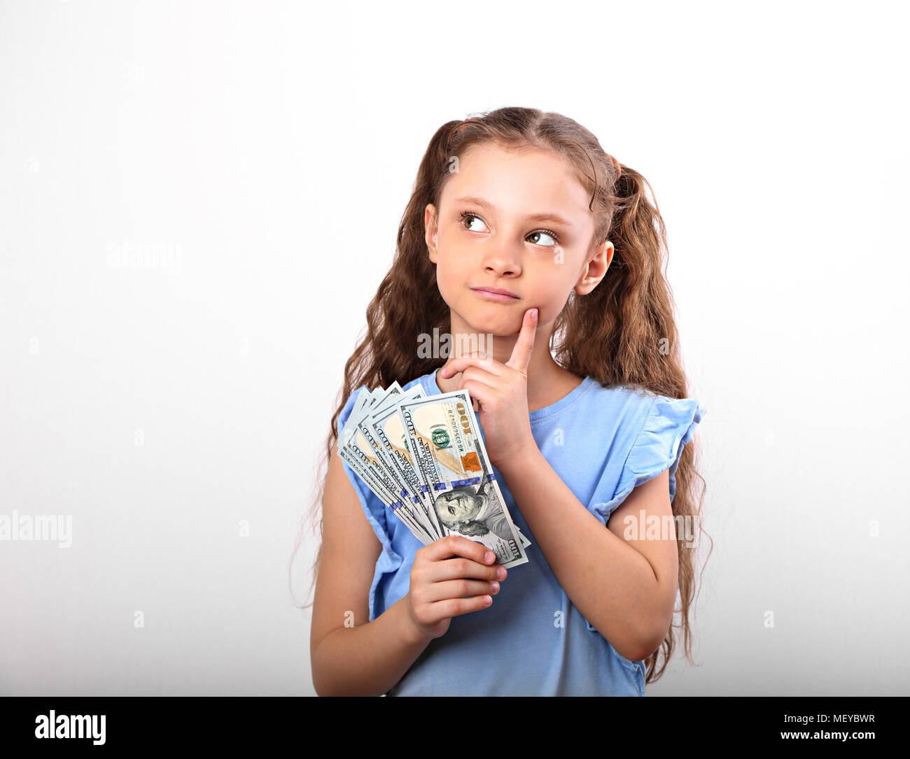 Happy smiling thinking rich kid girl holding money the hand and looking ...
