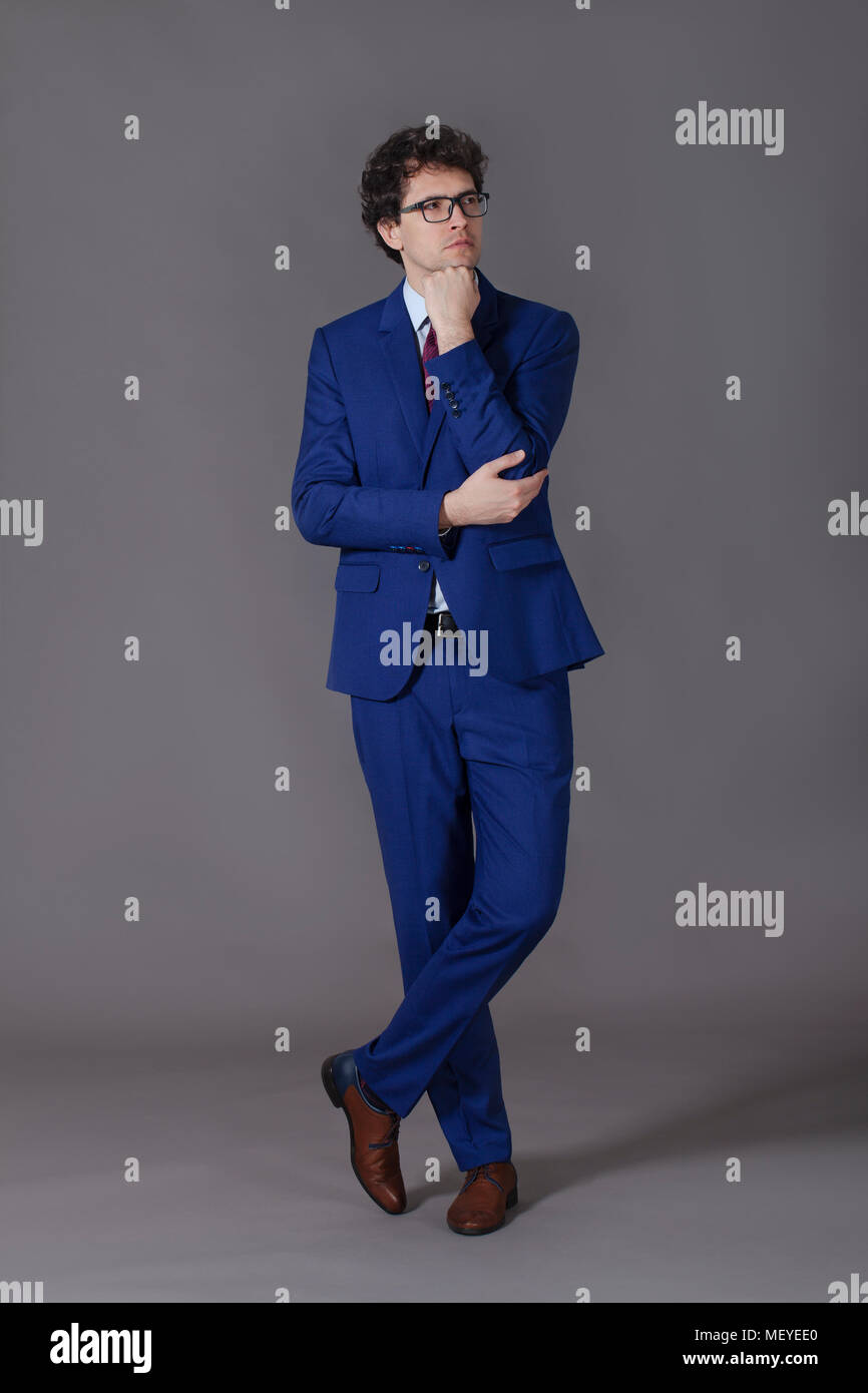 Man with crossing legs standing and keep his fist to beard Stock Photo ...