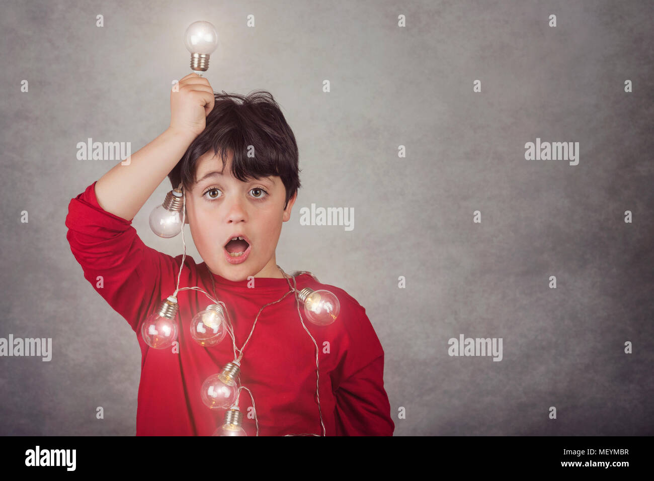 surprised boy with light bulbs on gray background Stock Photo - Alamy