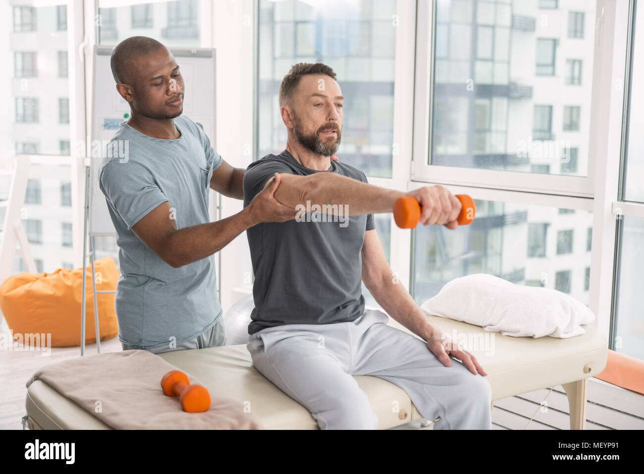 Pleasant nice doctor helping his patient Stock Photo - Alamy