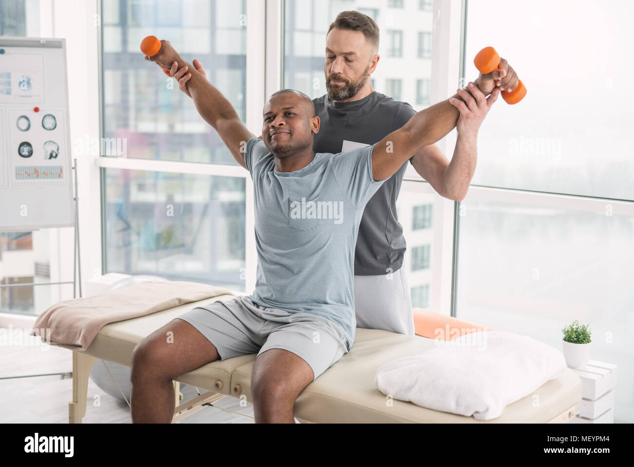 Serious nice man lifting his patients hands Stock Photo - Alamy