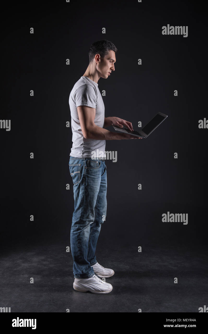 Pleasant intelligent man standing with a laptop Stock Photo - Alamy