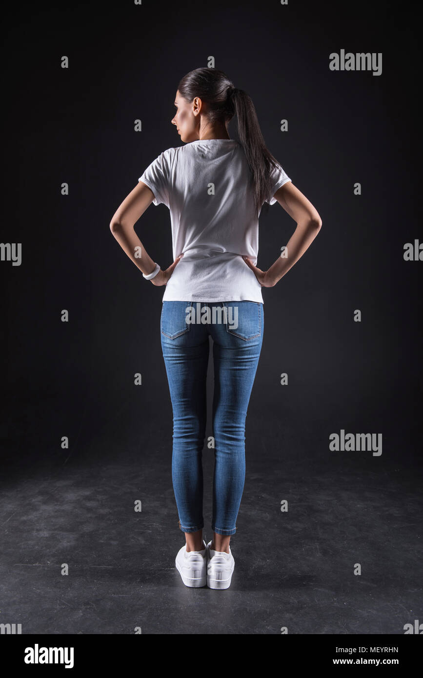 Confident young woman standing against black background Stock Photo - Alamy