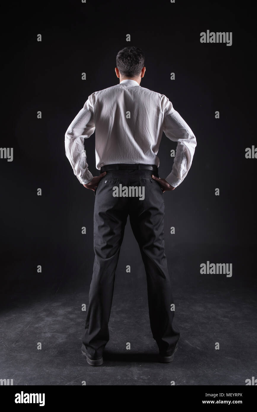 Serious smart man standing against black background Stock Photo - Alamy