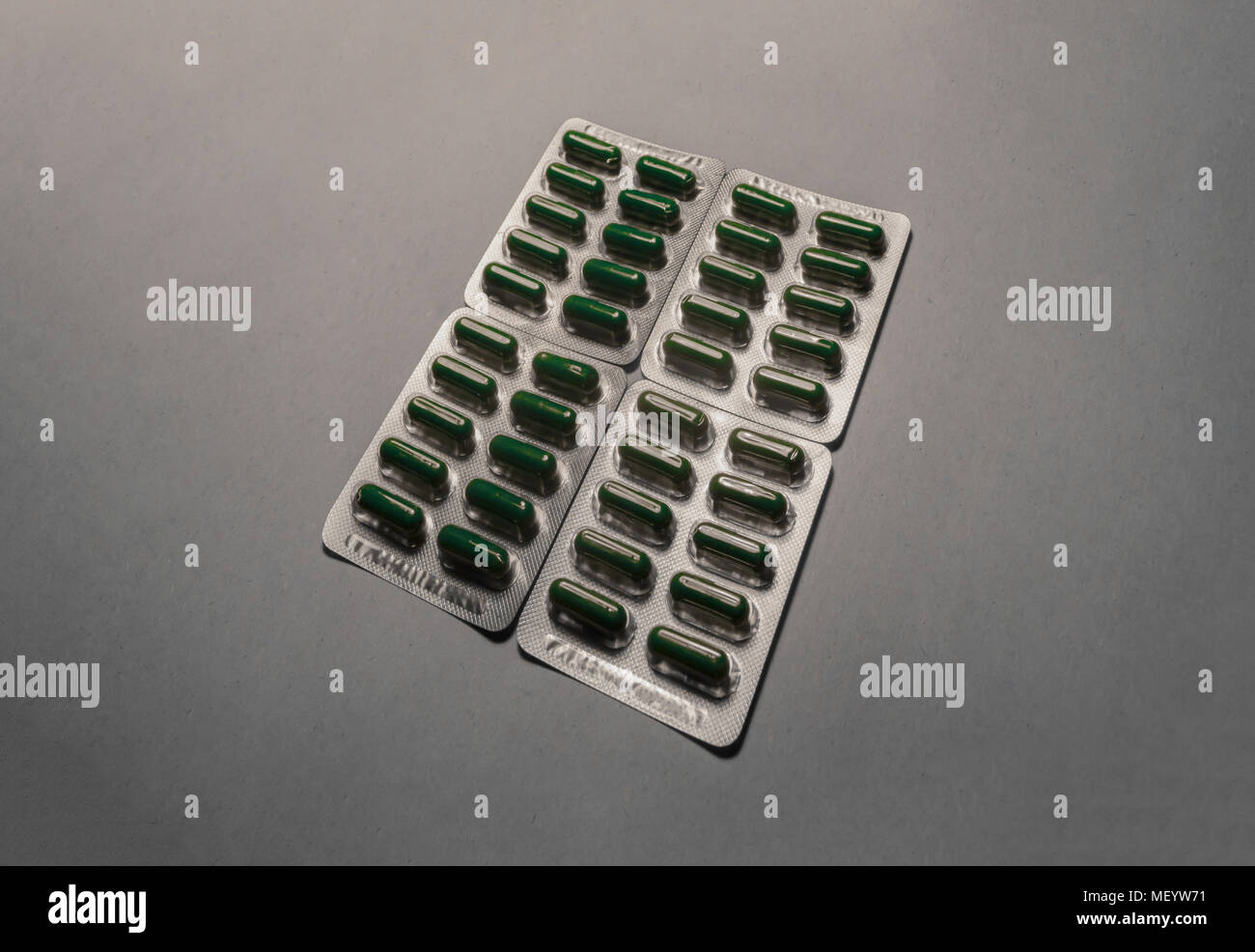 4 blisters of green medicine drugs lying one on the cardboard Stock ...