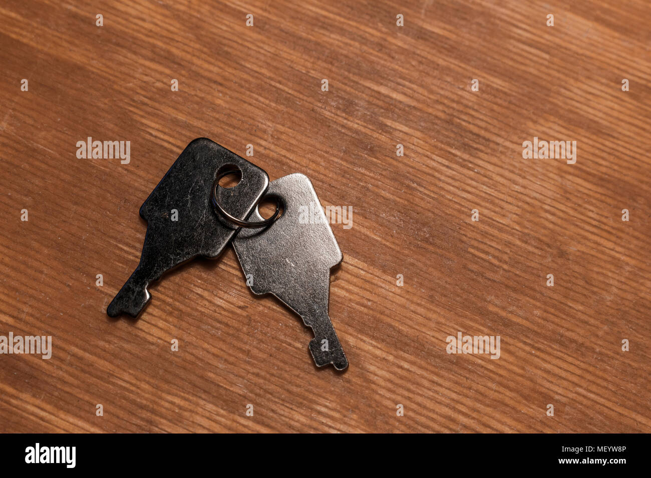 Two small keys on the old wooden table with a lot of scratches. Image ...