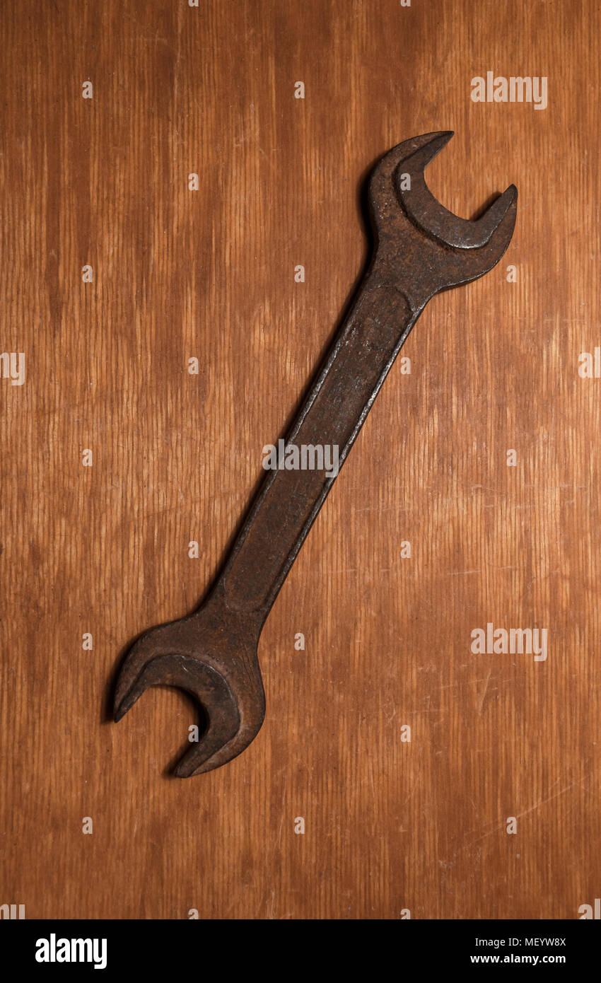 Old rusty spanner on the scratched wooden background. One wrench on the ...