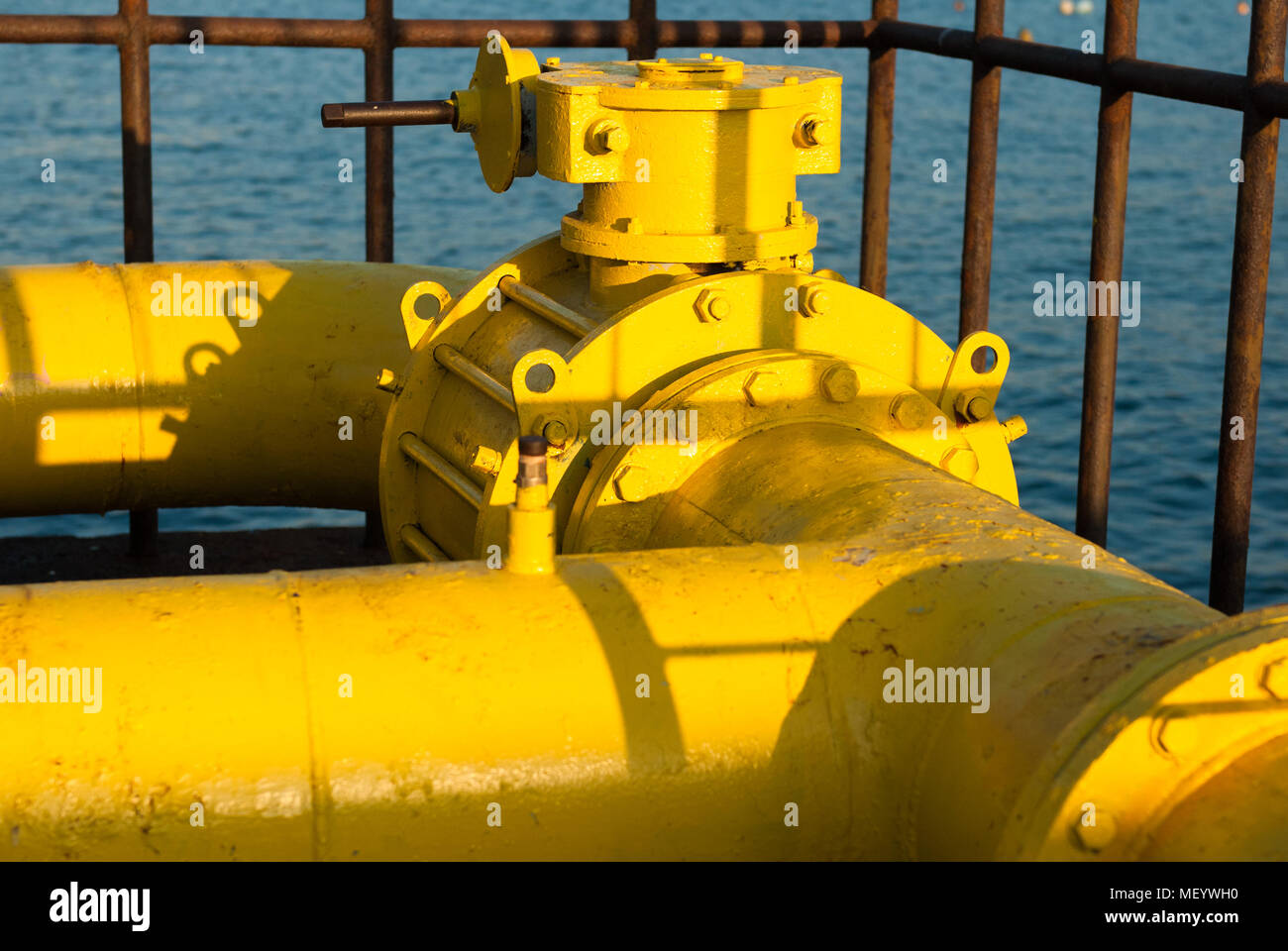 yellow pipeline with pump in cage on sea background Stock Photo - Alamy
