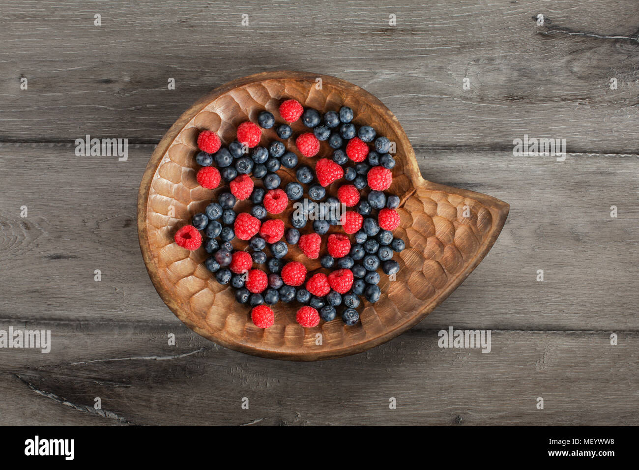 Table top view on mixed blueberries and raspberries in vintage carved ...