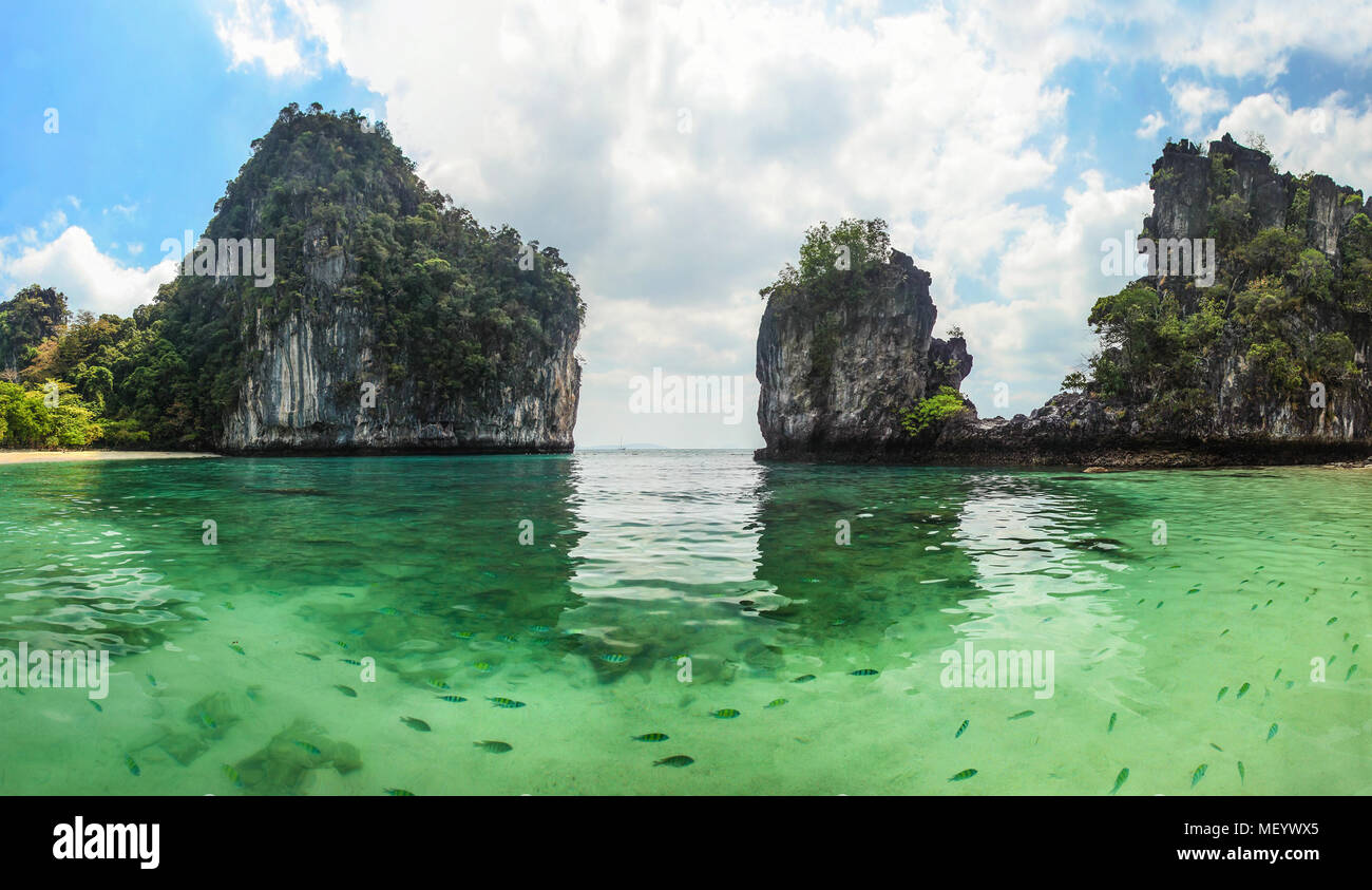 Panorama of sharp karst cliffs rising from water with clear green sea ...