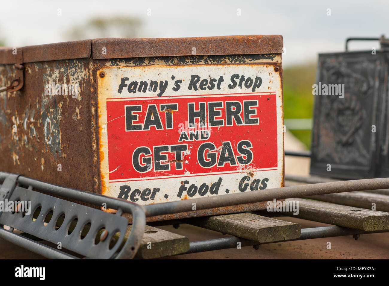 Rusty storage box on car roof with a red Eat Here and Get Gas sign ...