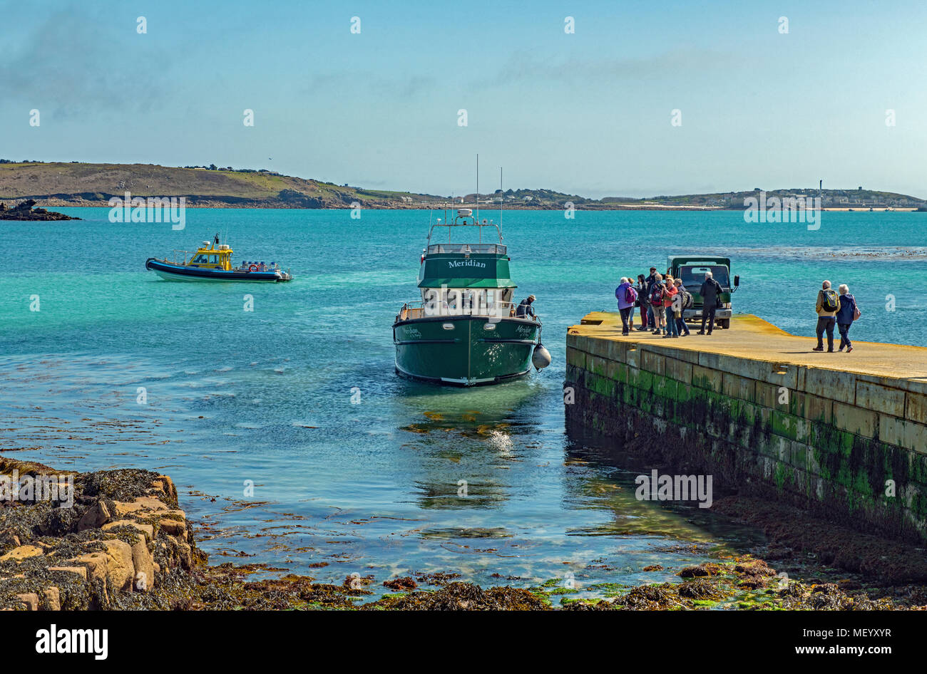 Boats approaching and leaving Carn Near quay on Tresco in the Isles of ...
