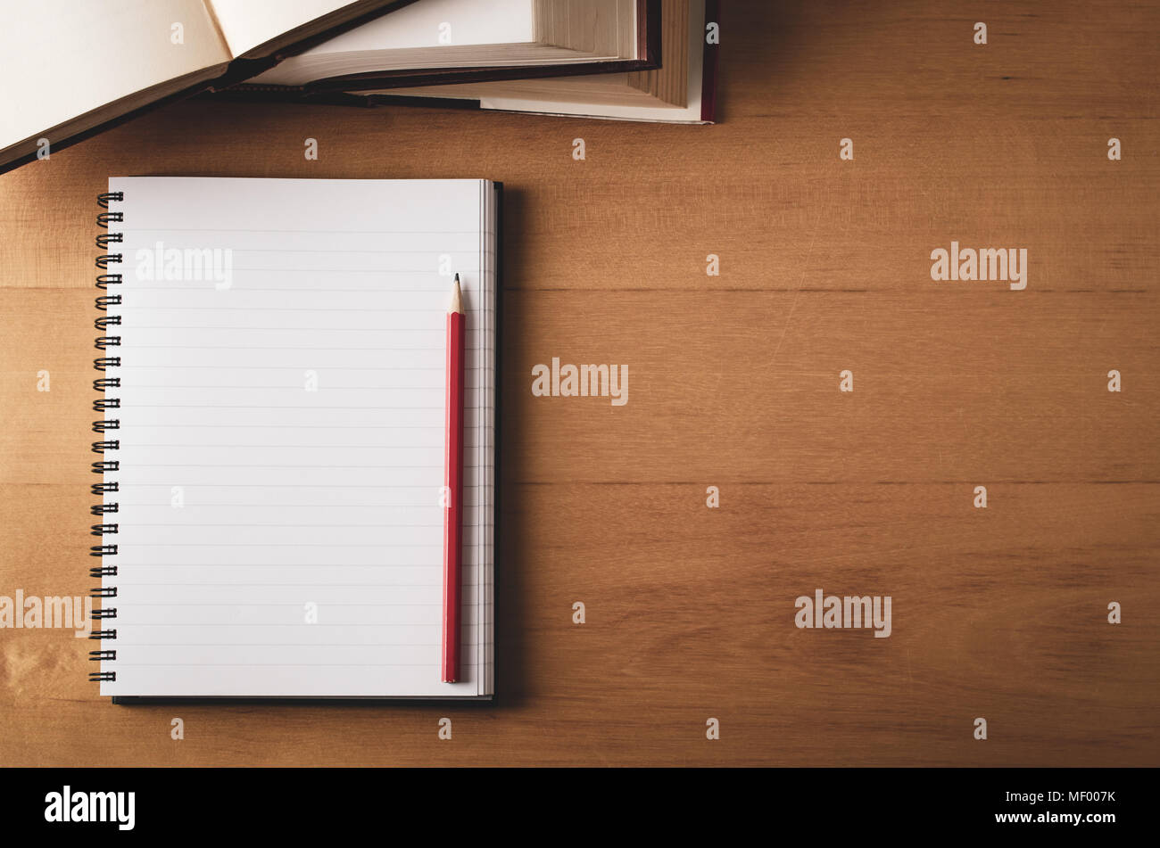 Overhead of desk study scene with pencil on blank page of opened ...
