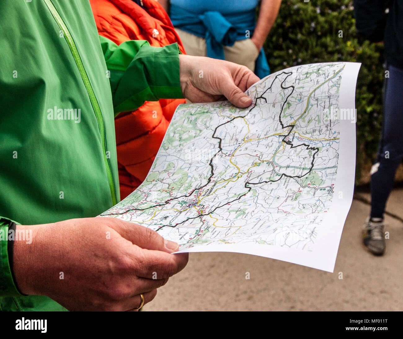 Map showing a hiking course, hands of a hiker holding the map before ...