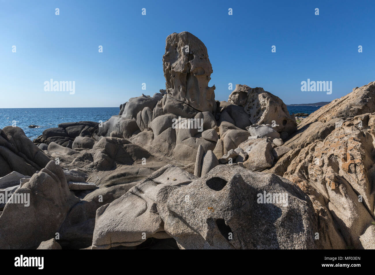 The sun shines on the rocks eroded by wind framing the blue sea Punta ...