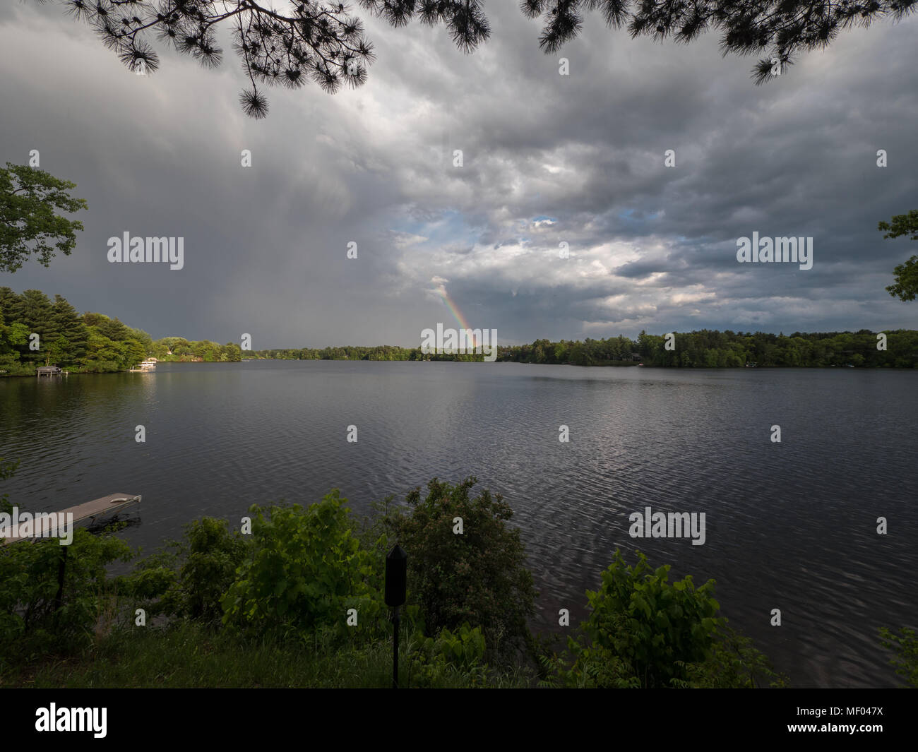 Rainbow reaches across the lake after a rain Stock Photo - Alamy