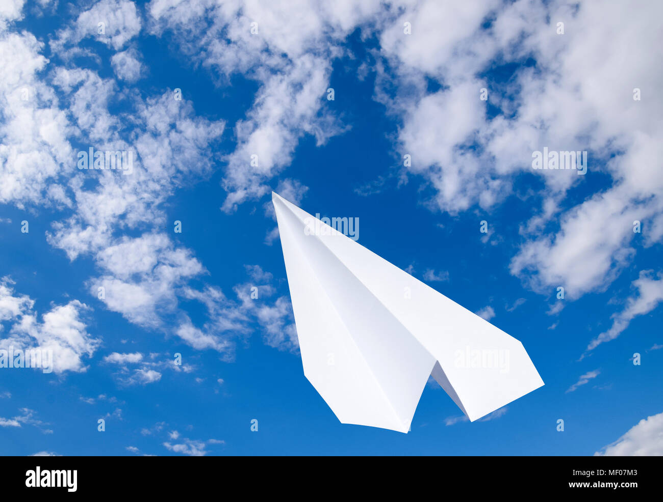 White paper airplane in a blue sky with clouds. The message symbol in ...