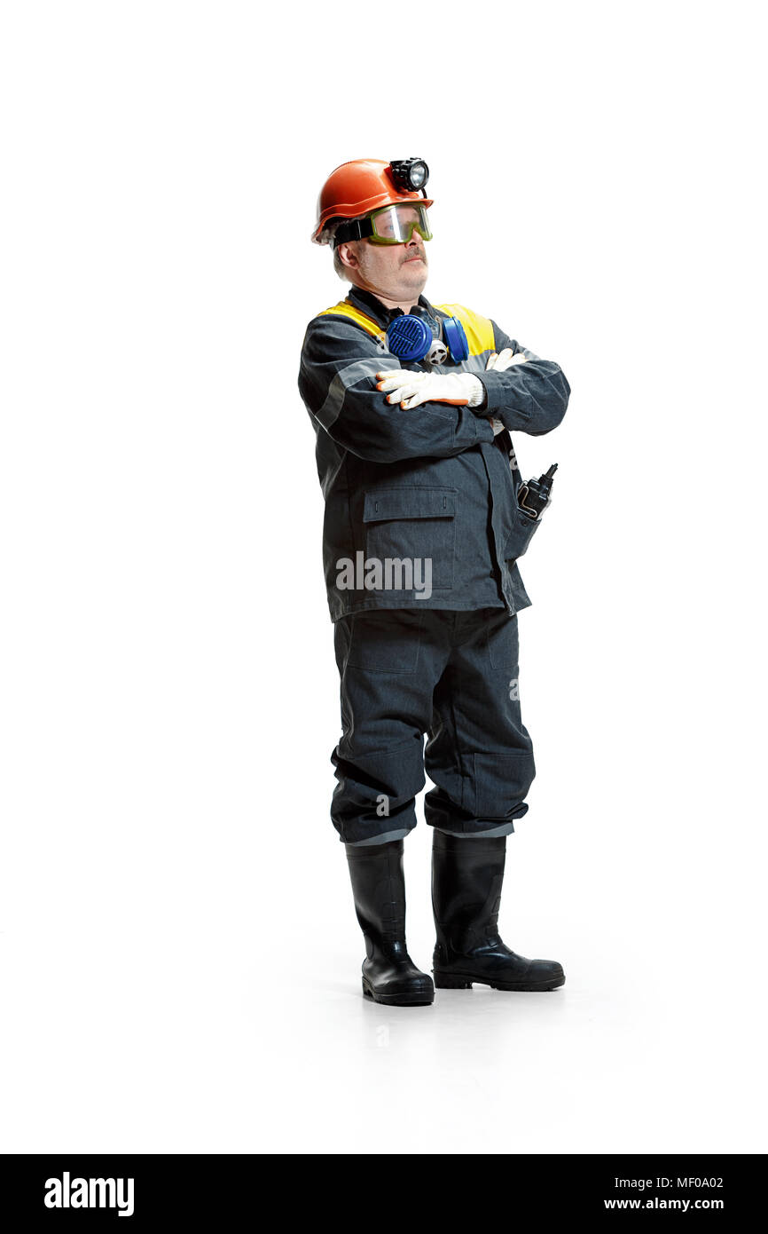 The studio shot of senior bearded male miner standing at the camera on ...