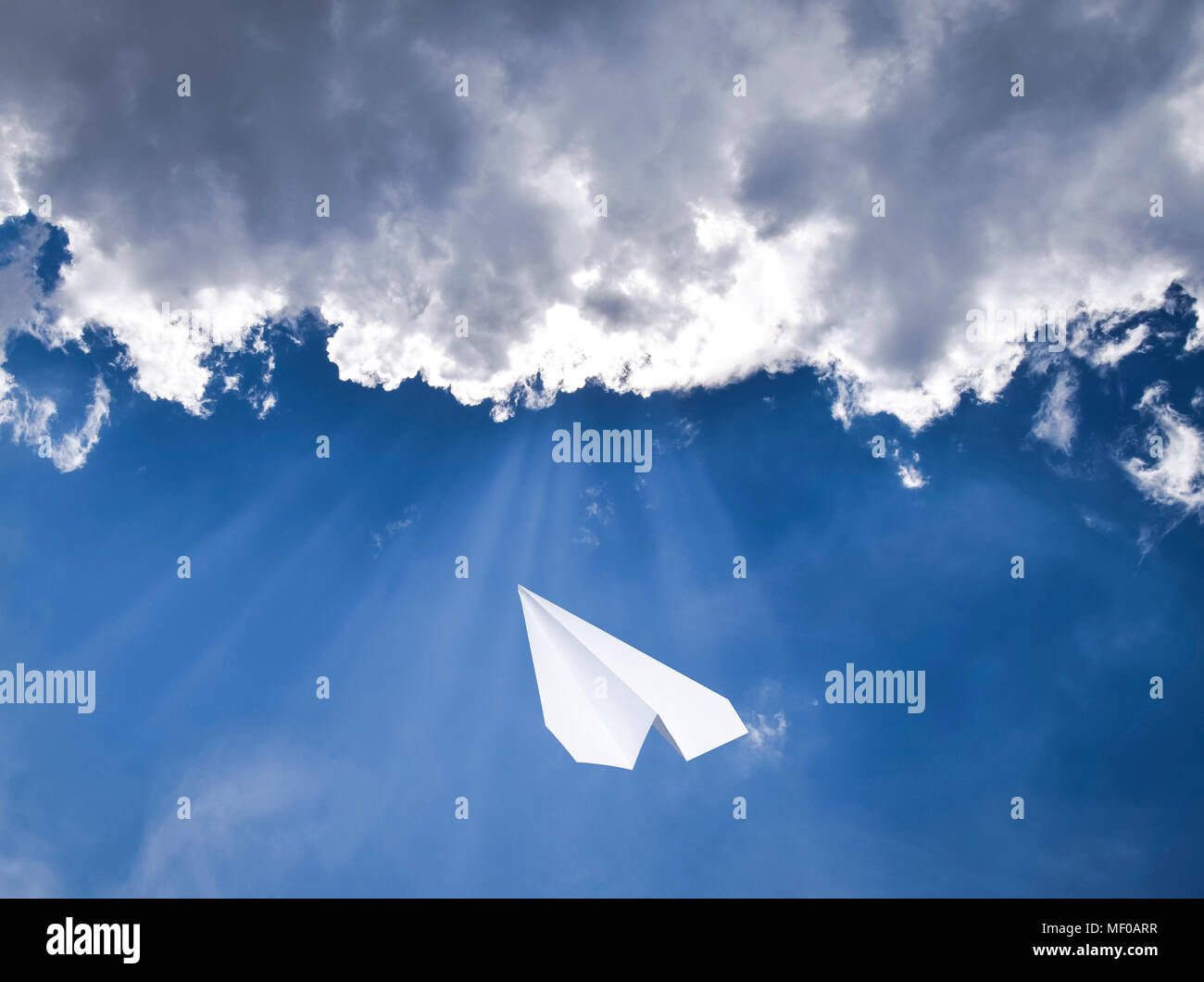 White paper airplane in a blue sky with clouds. The message symbol in ...