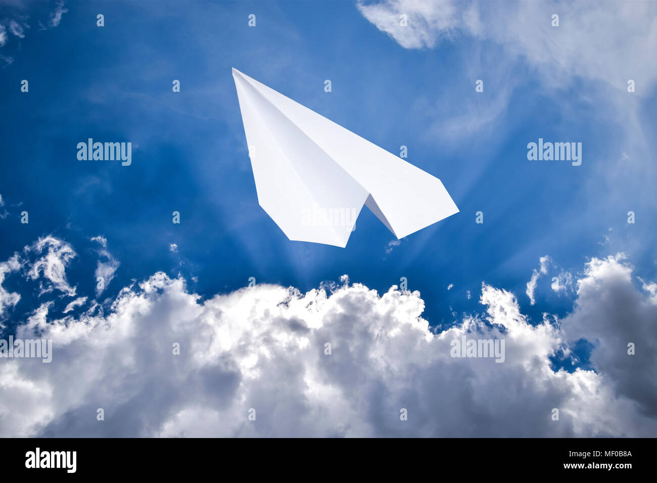 White paper airplane in a blue sky with clouds. The message symbol in ...