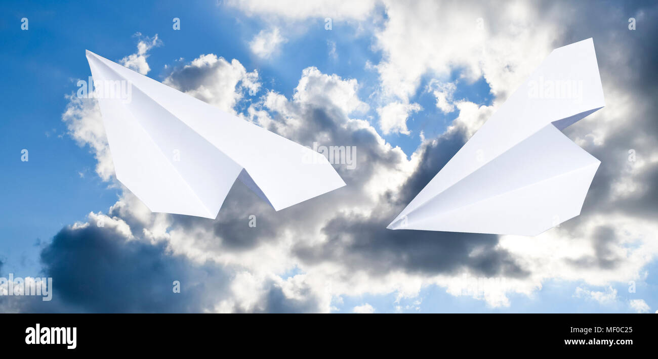 White paper airplane in a blue sky with clouds. The message symbol in ...