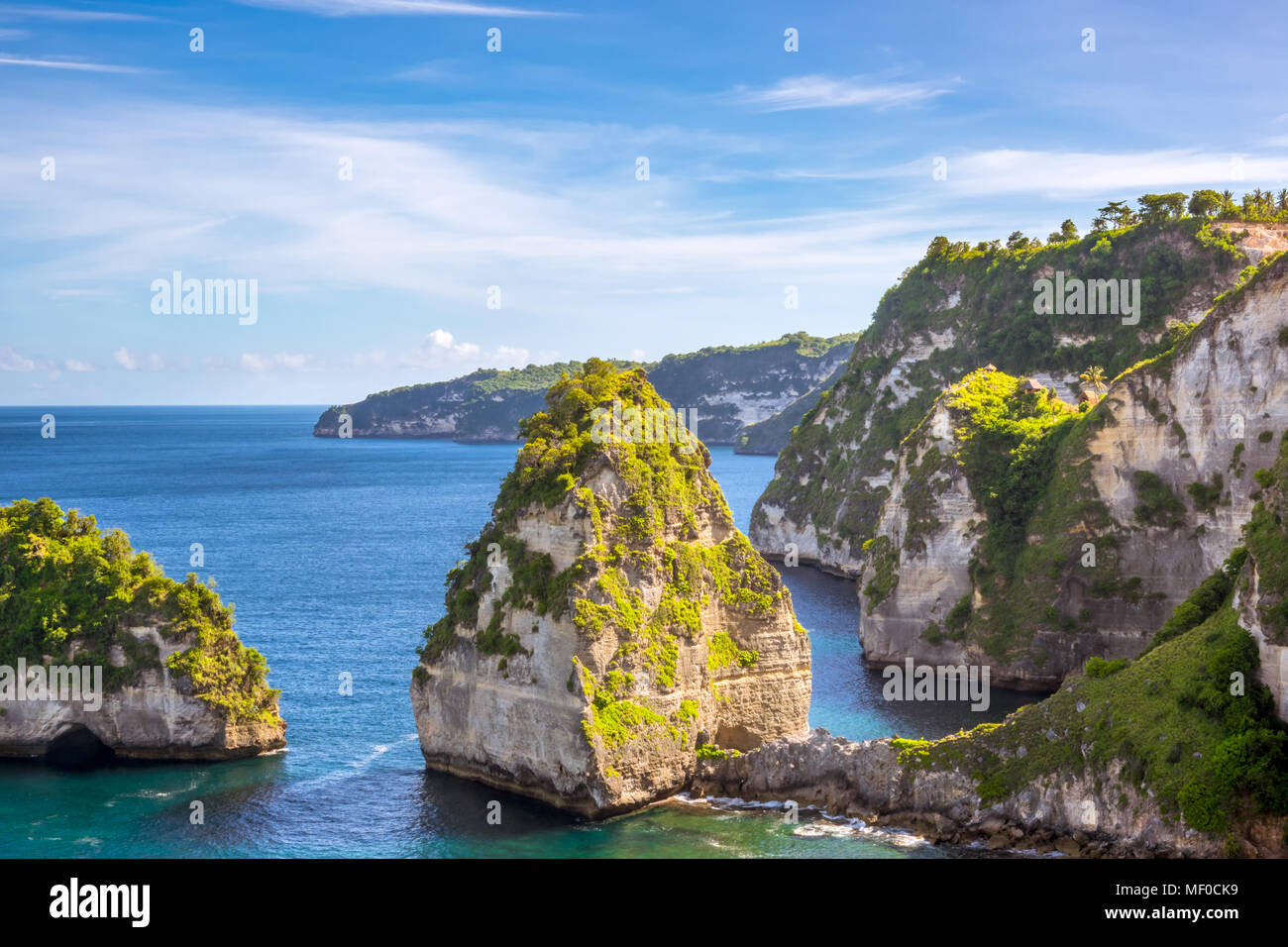 Indonesia. The ocean shore of a rocky island. A few huts on top of a ...
