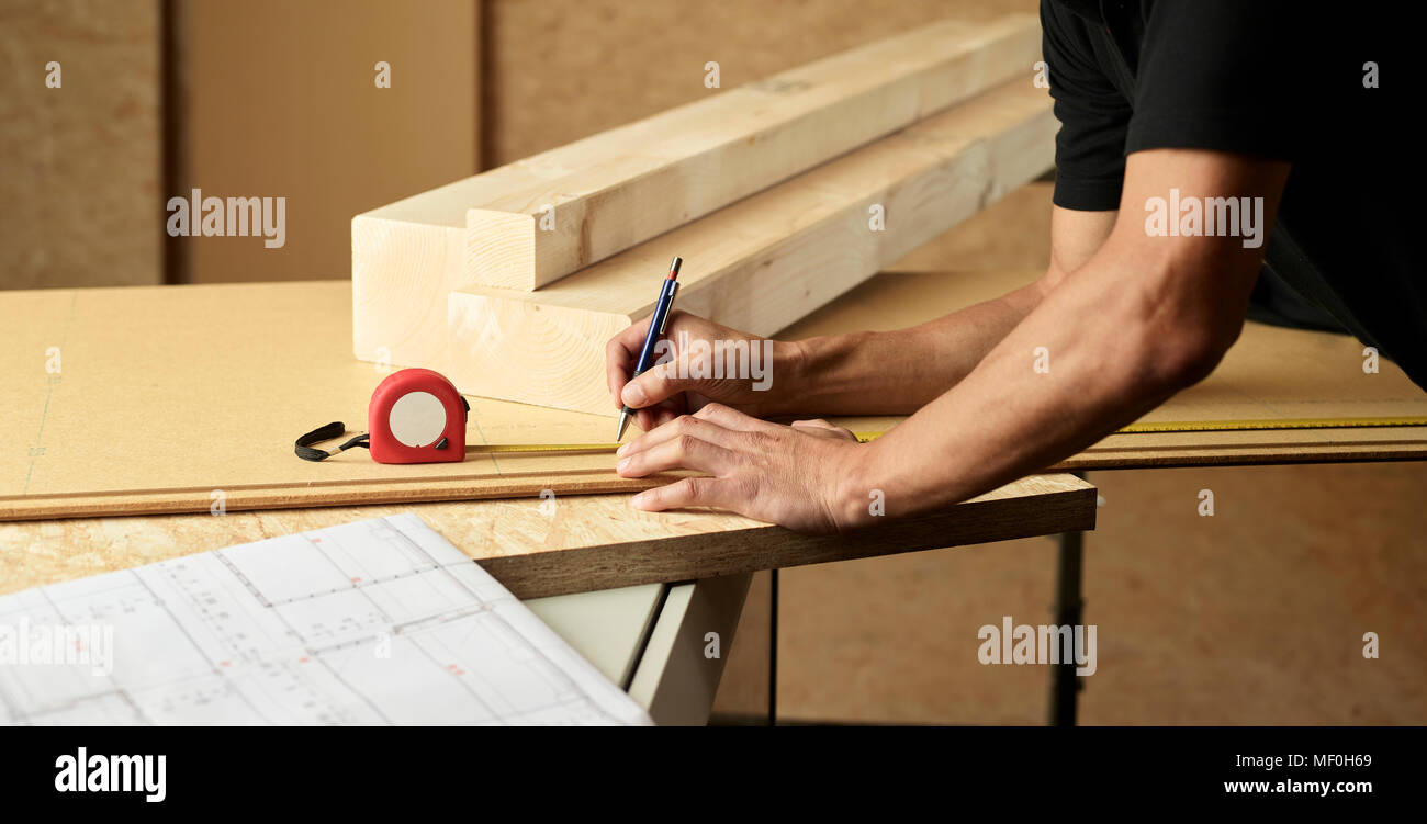 Worker marking wood with pencil, tape measure Stock Photo - Alamy