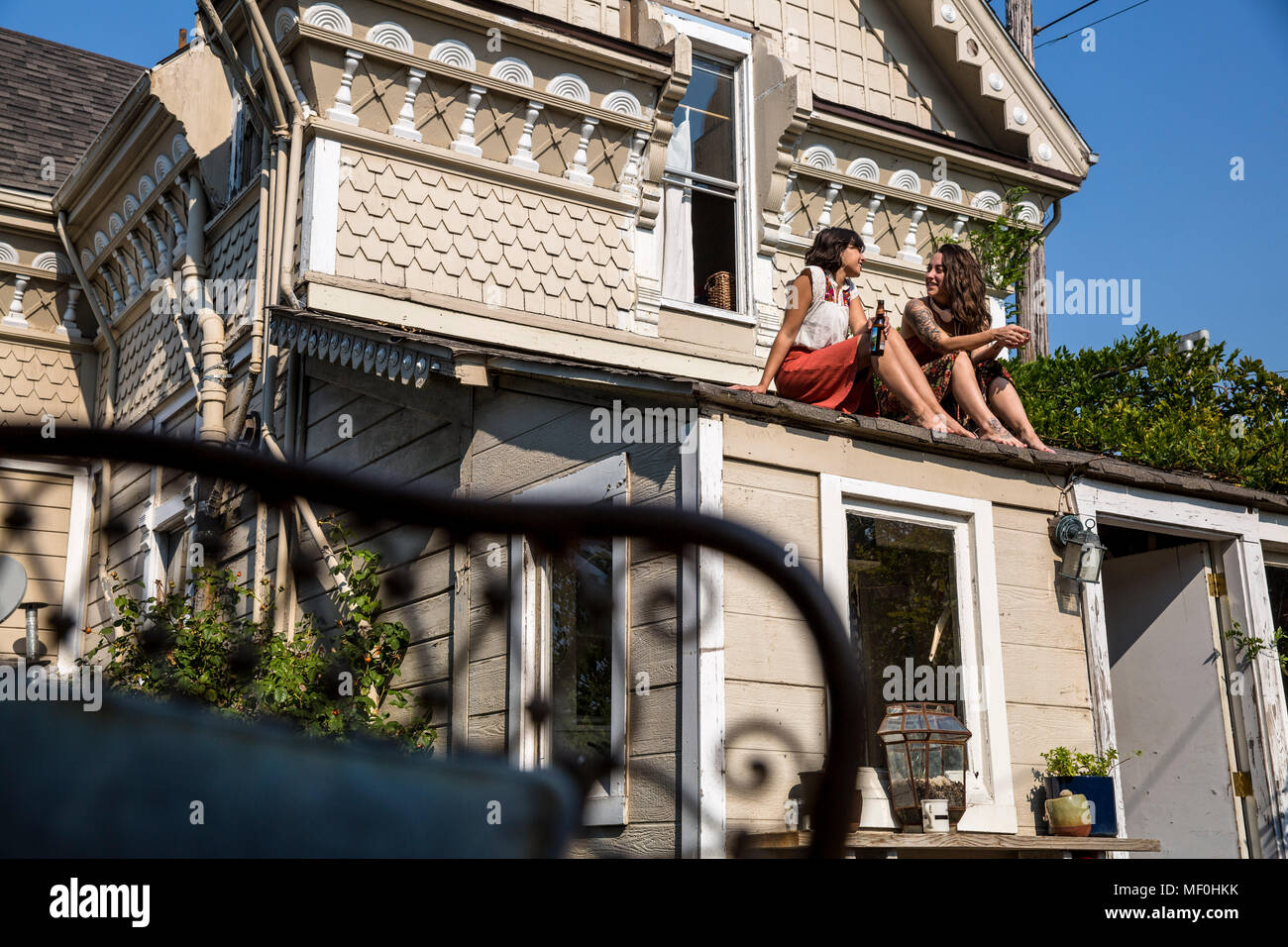 Two young women sitting on roof Stock Photo - Alamy