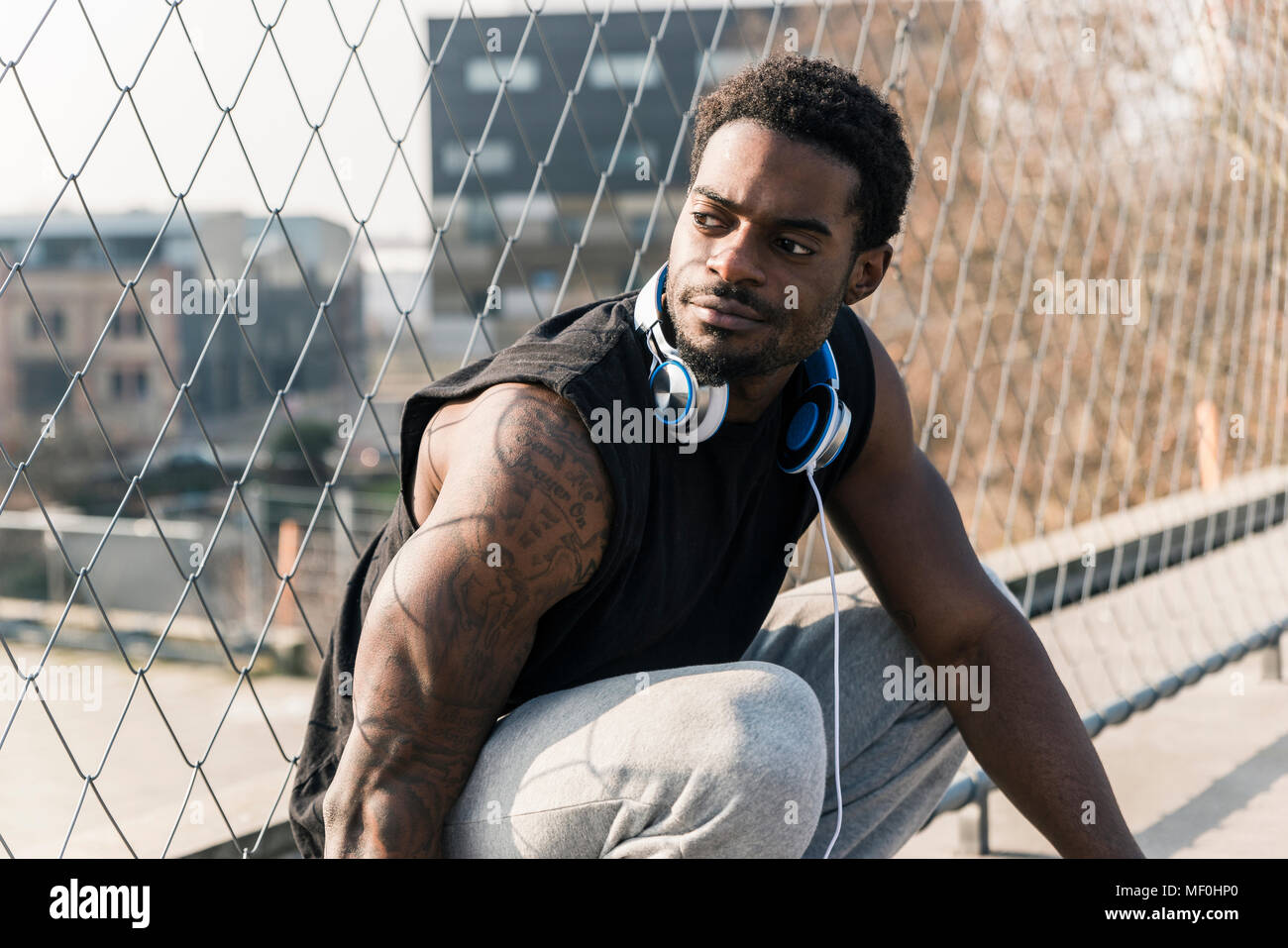 Confident young man on court crouching at fence Stock Photo - Alamy
