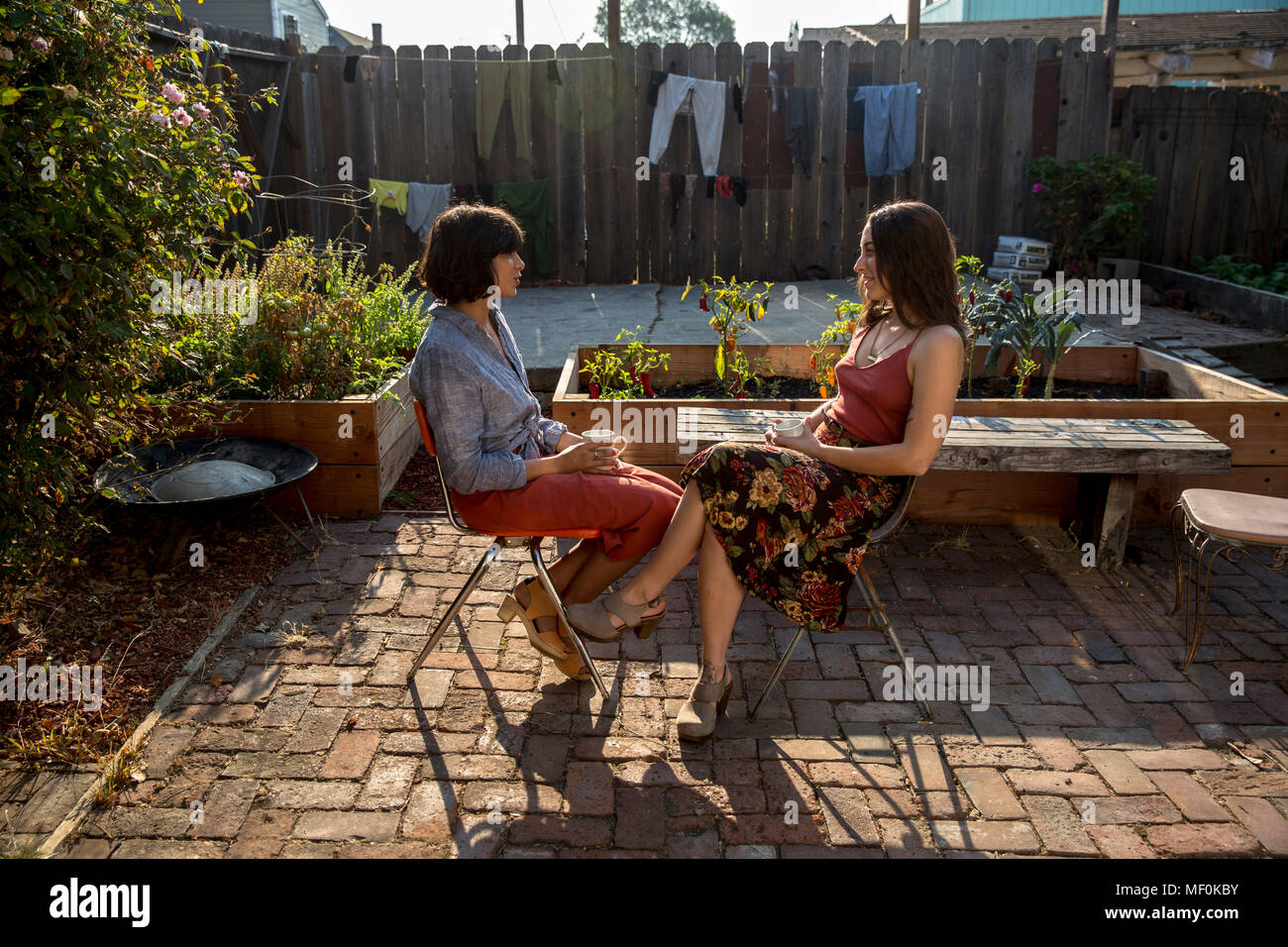 Two young women sitting in backyard talking Stock Photo - Alamy