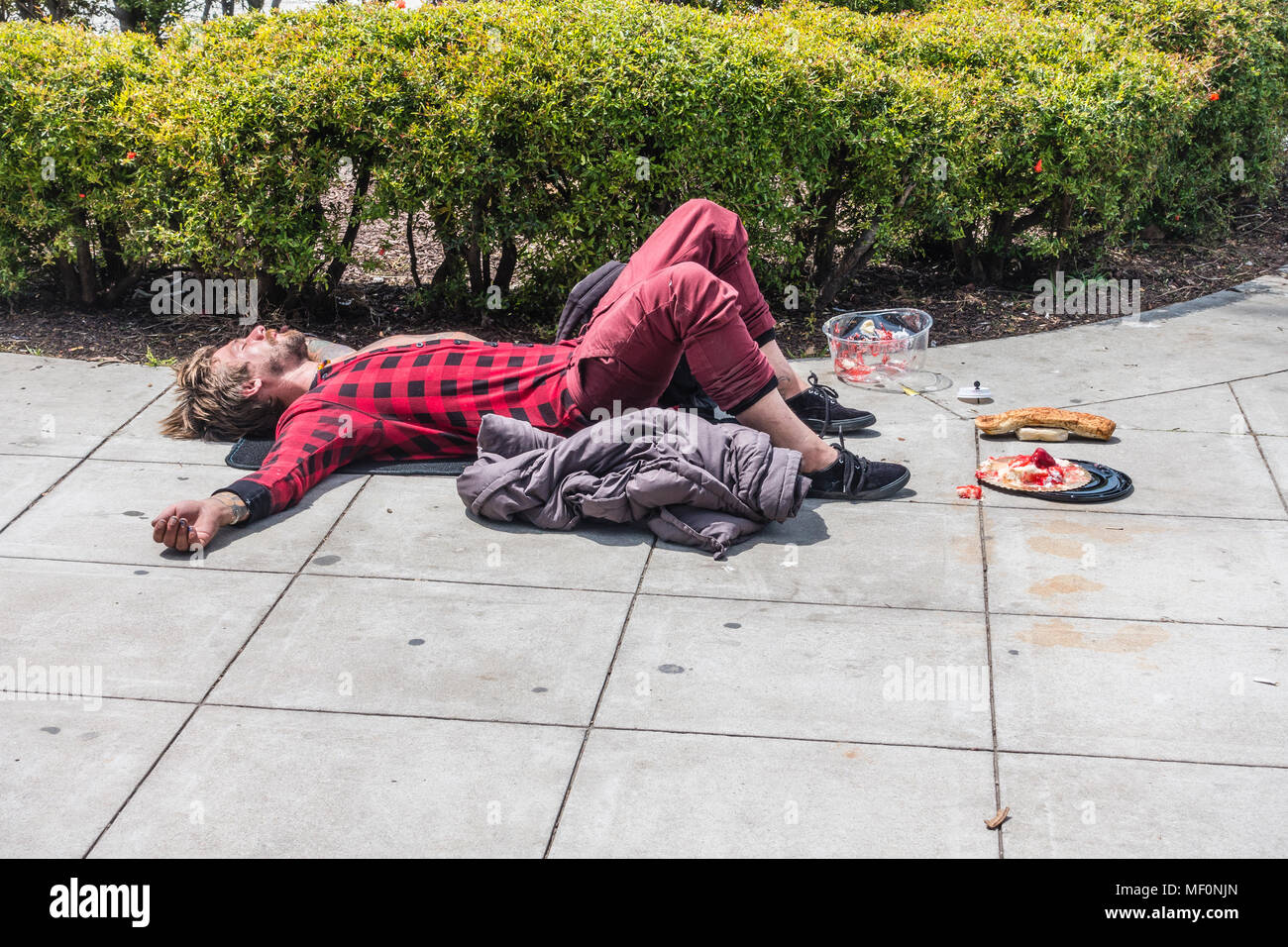 Homeless person passed out on the sidewalk, spread eagle, with his arms ...