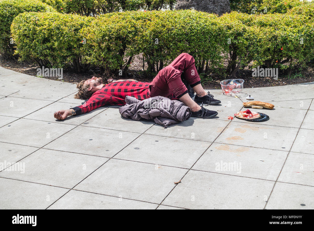 Homeless person passed out on the sidewalk, spread eagle, with his arms ...