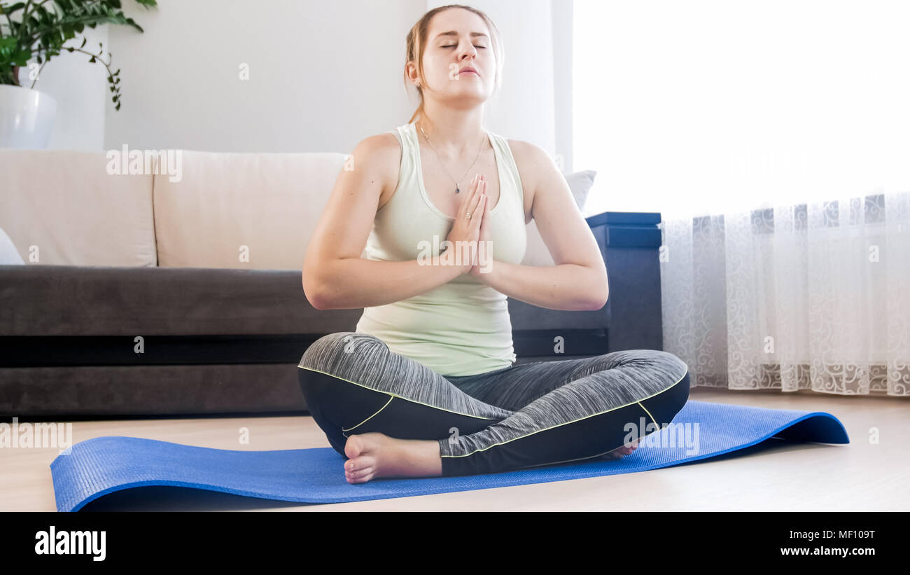 Beautiful young woman sitting in lotus position and breathing deeply ...