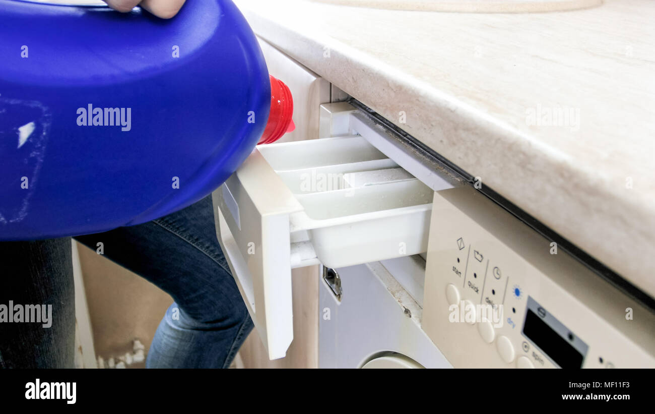 Closeup image of young woman pouring liquid detergent in washing ...