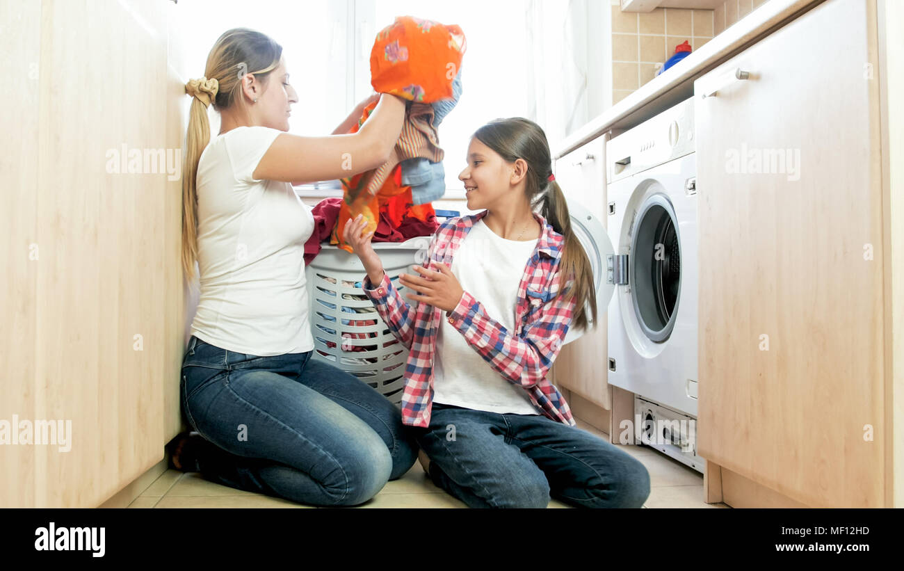 Beautiful Young Mother With Daughter Loading Clothes In Washing Machine