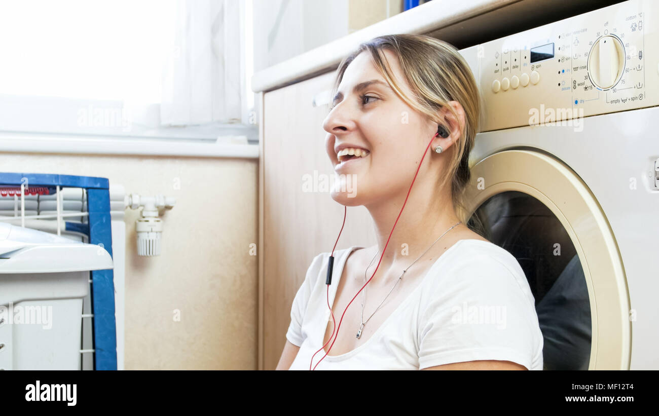 Happy smiling housewife with earphones singing while waiting for ...