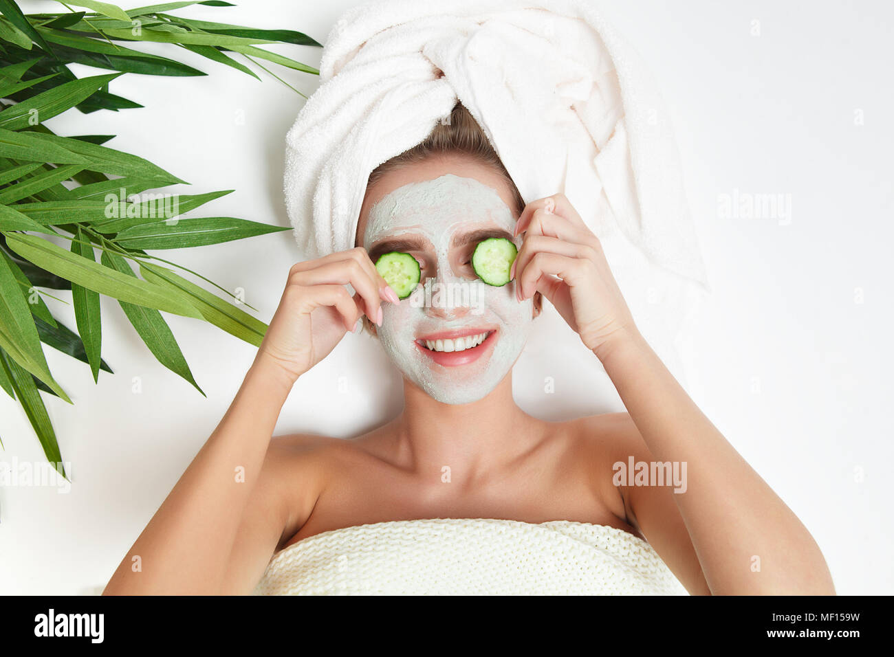 Portrait of beauty woman laying with towel on the head, cucumber on her eyes, facial mask. Spa ...