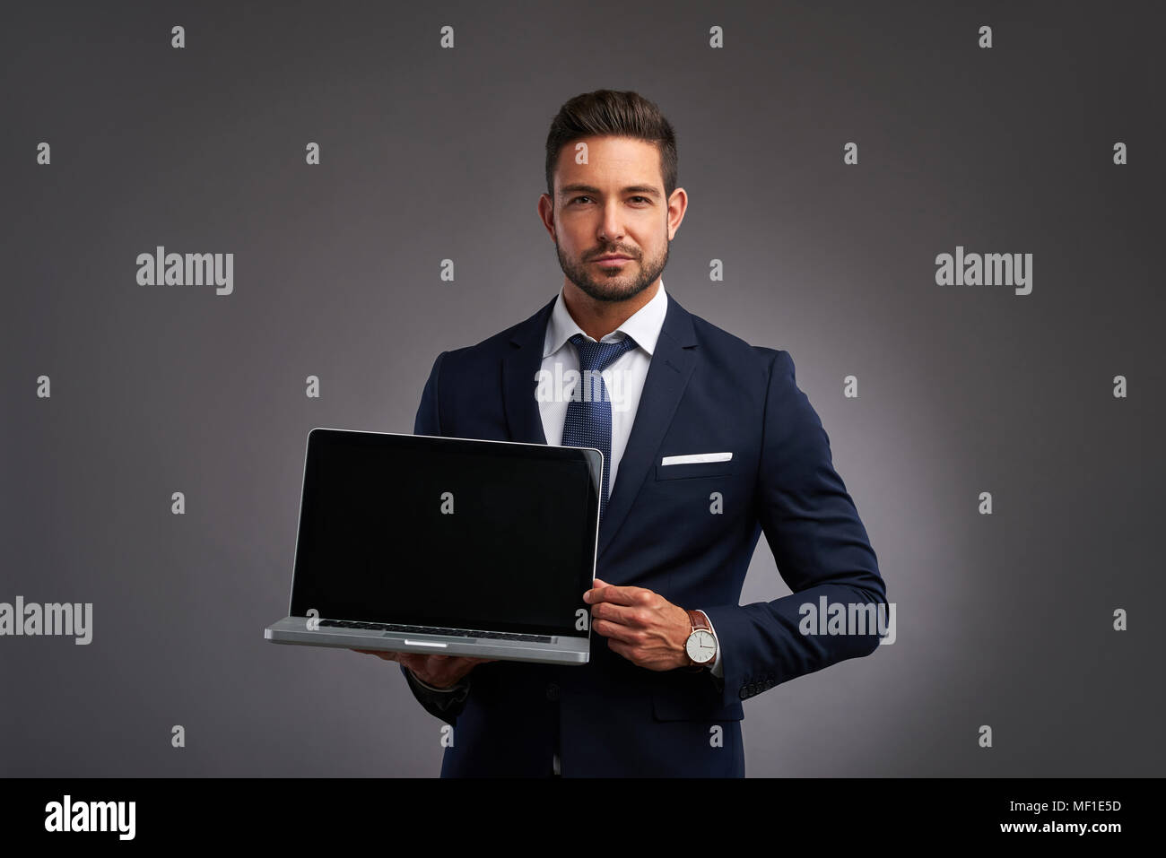 An elegant handsome young man holding and showing the screen of a ...