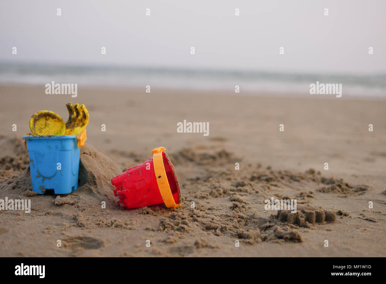 red and blue toy bucket for kid on sand beach Stock Photo - Alamy