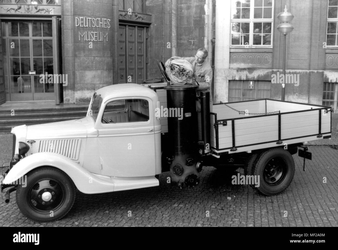 A man fills the Imbert gas generator of a Ford V8 truck with wood gas ...