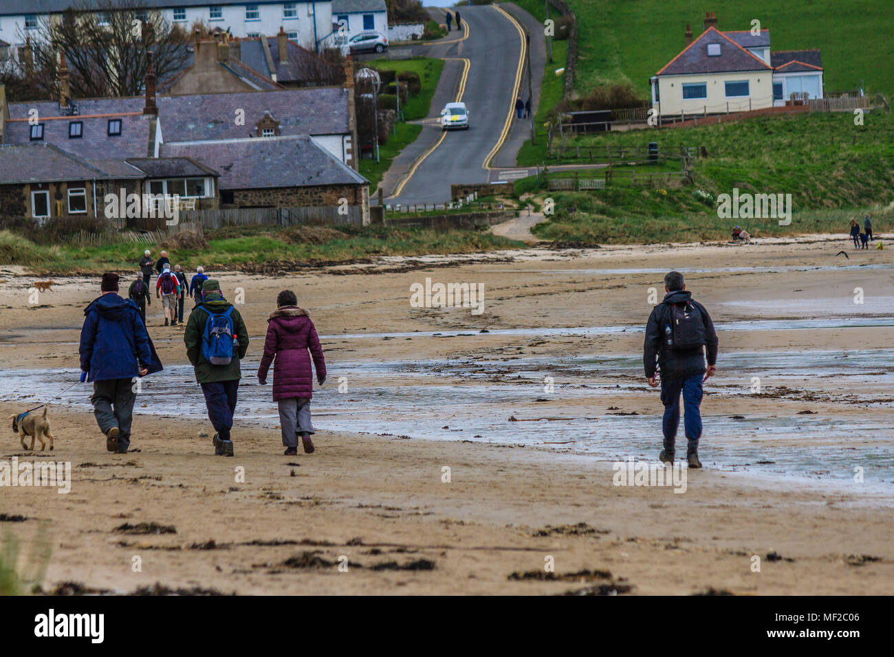 People walk on the beach on a chilly day at Low Newton-by-the-Sea ...