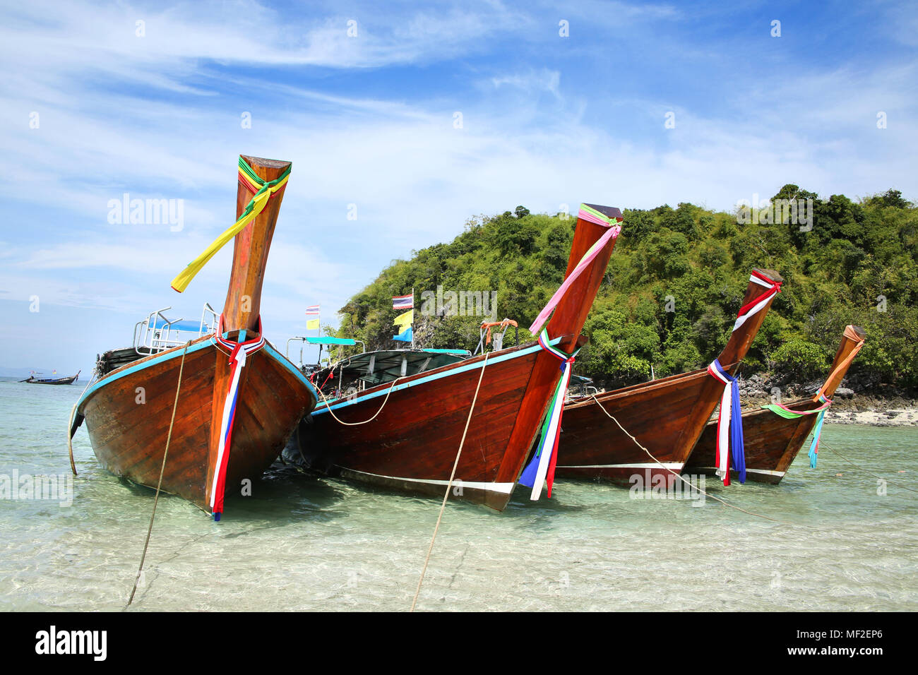 Thai fishing boats tied up on the beach with a beautiful island in the ...