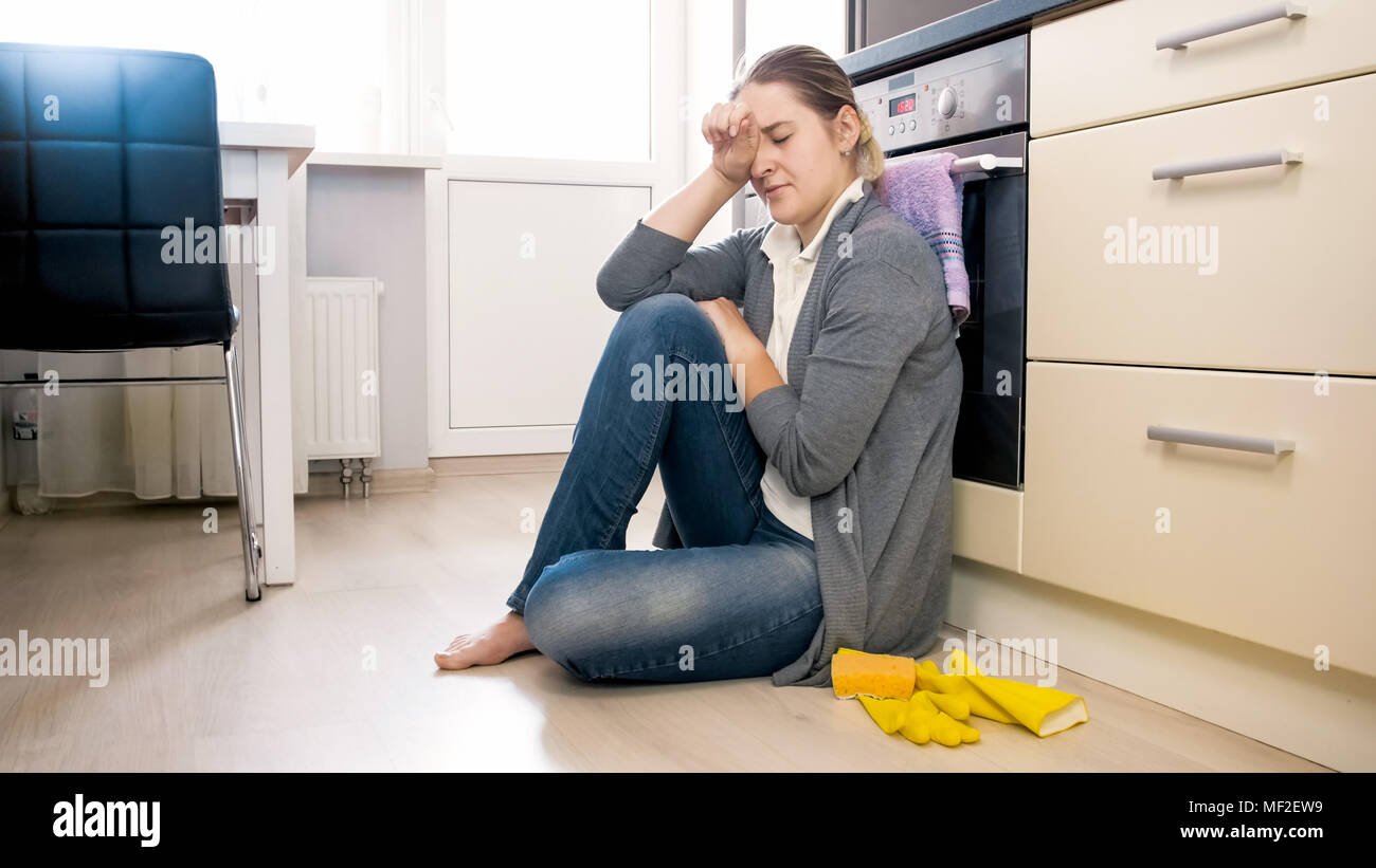 Young woman crying on floor after doing housework Stock Photo - Alamy