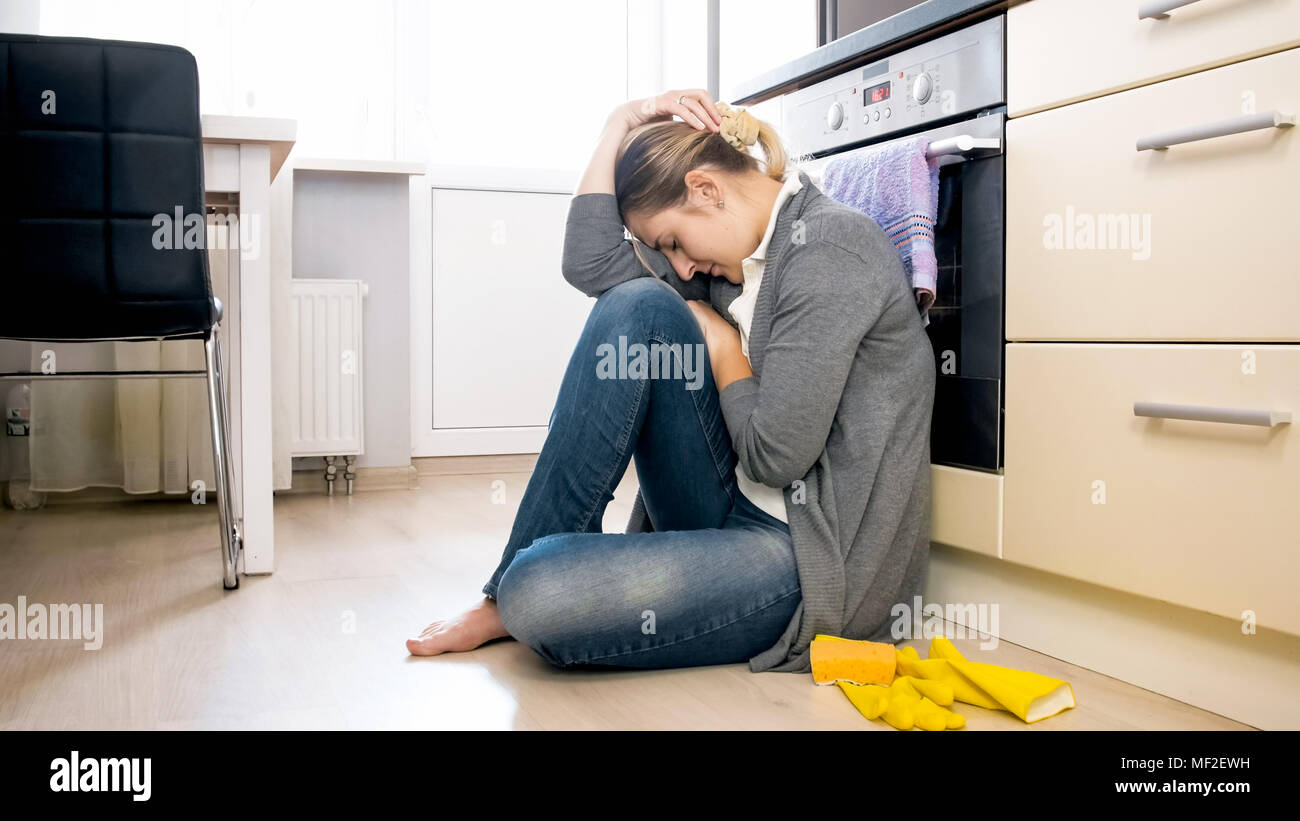 Exhausted young woman sleeping on floor at kitchen Stock Photo - Alamy
