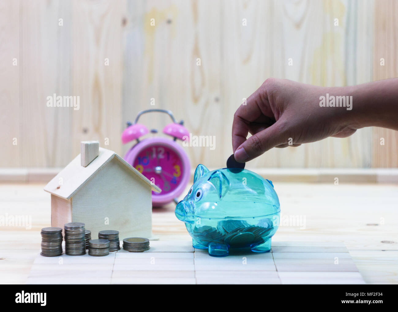 hand of women drop coins in a clear piggy on the wooden table and ...