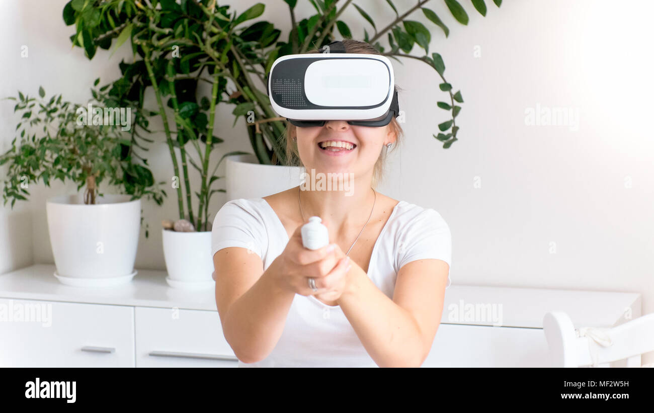 Portrait of laughing young woman playing video games in VR helmet Stock ...